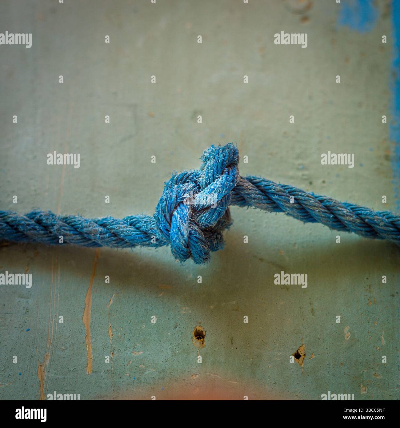 A close-up view reveals an intricately tied blue rope knot resting on a ...
