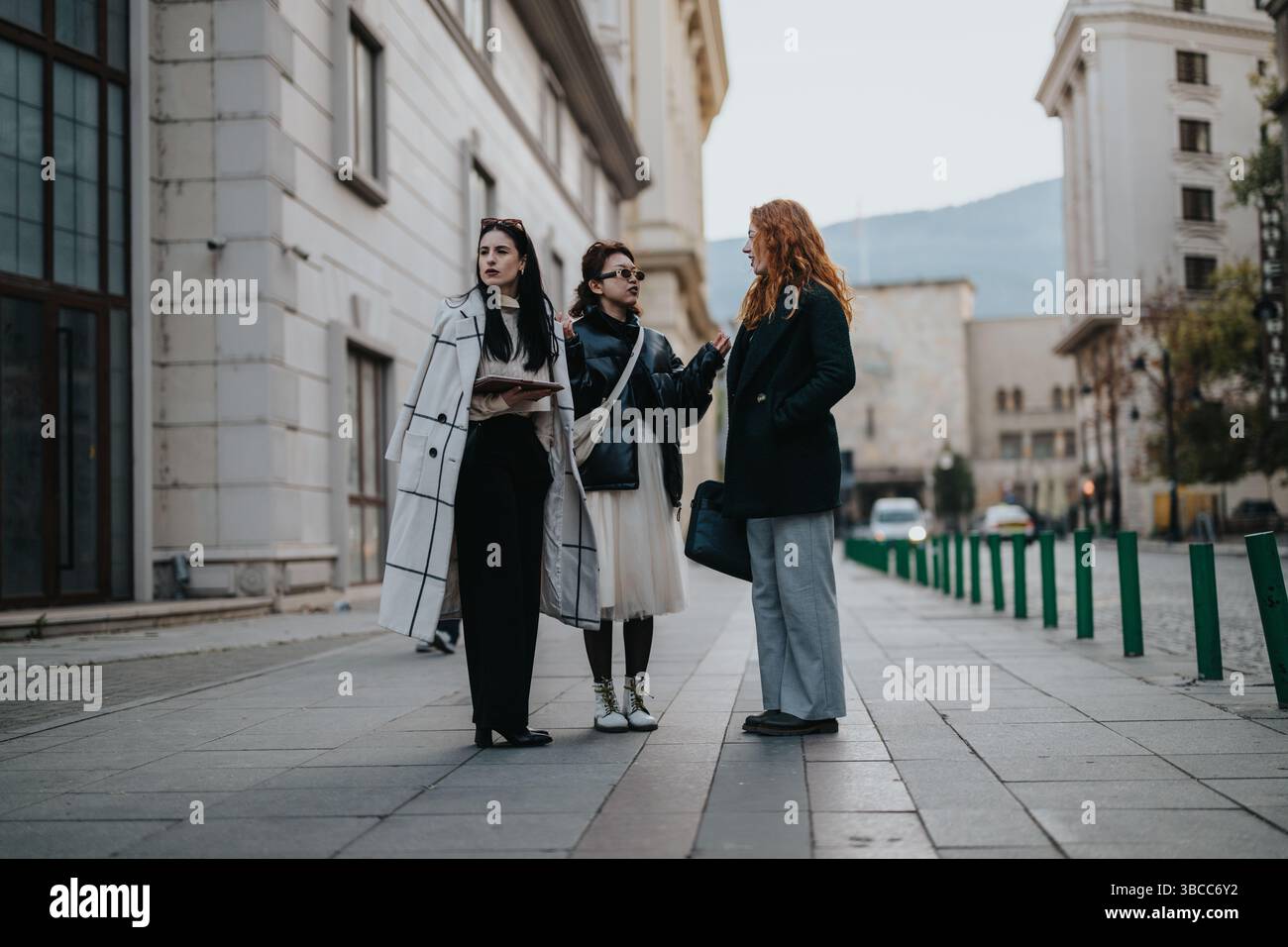 Three professional businesswomen conversing in an urban outdoor setting ...