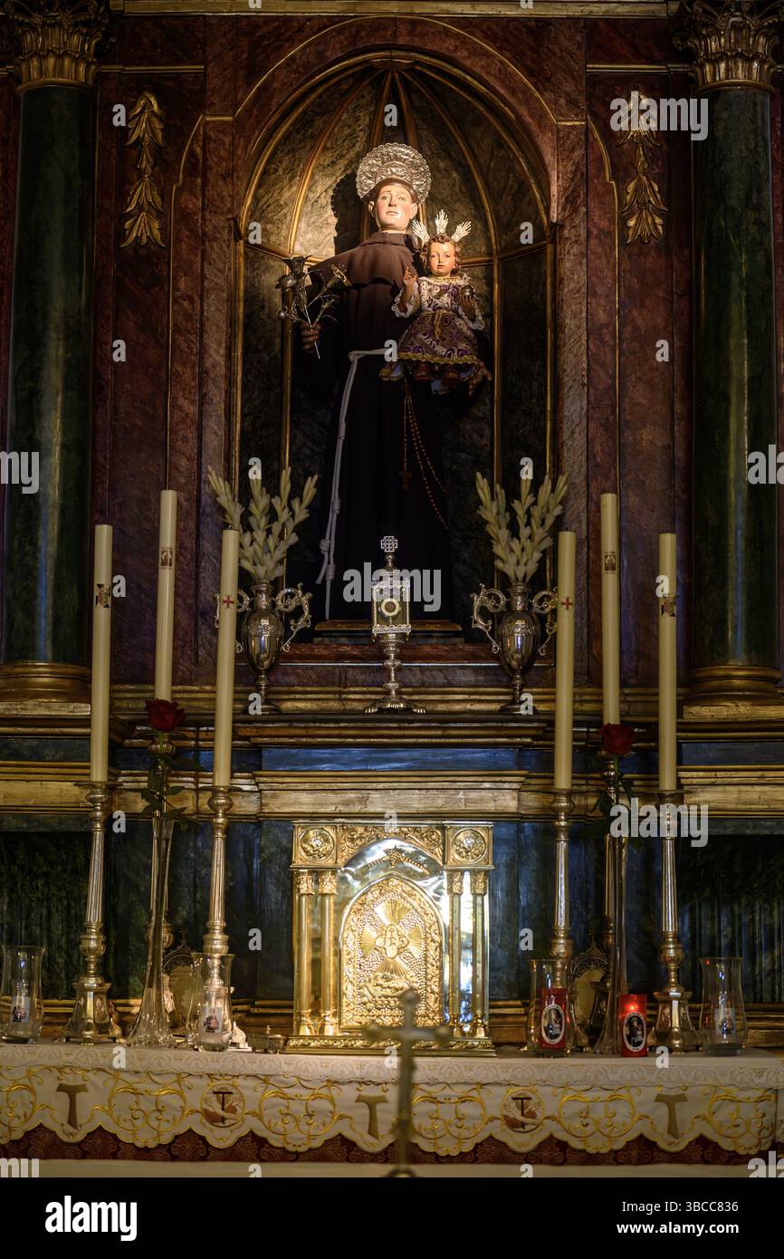 Baroque altar of San Antonio with candles, statue, and golden ...