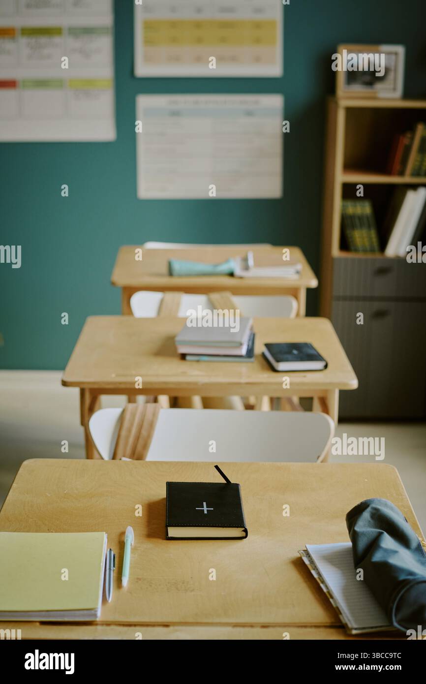 Classroom setting with multiple wooden desks, study materials, and ...