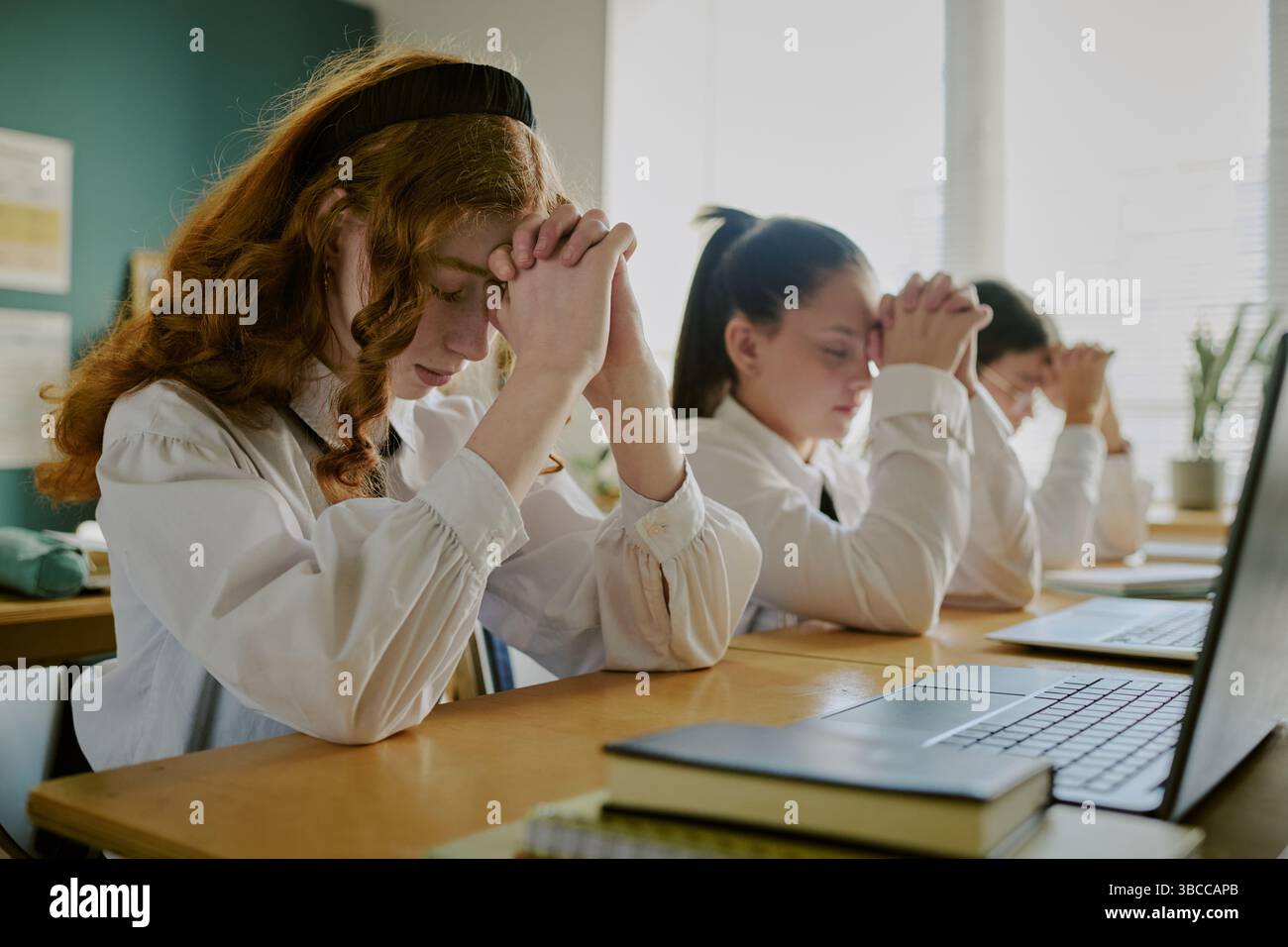 Group of students in school uniforms praying with closed eyes and ...