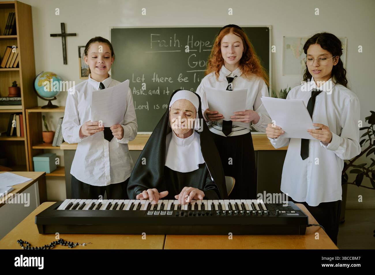 Group of students standing around senior nun playing keyboard ...