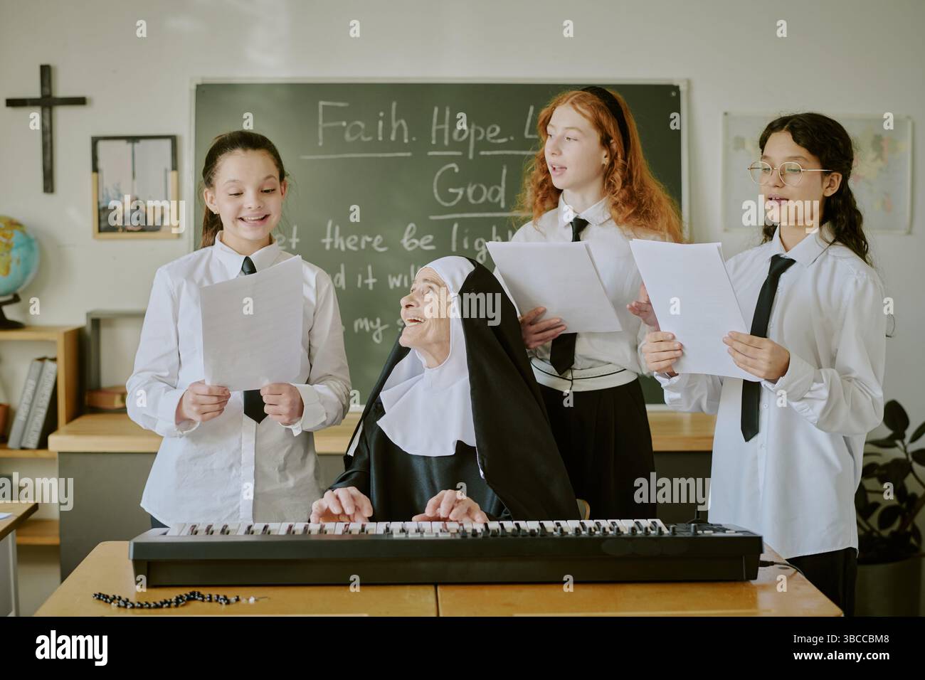 Group of young students standing around a keyboard performing music in ...