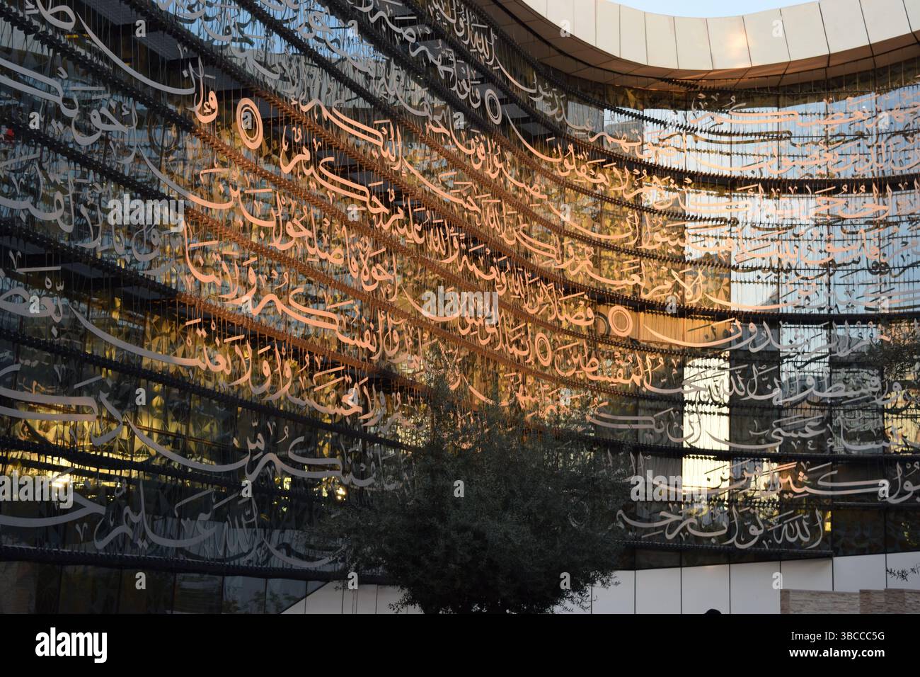 Arabic calligraphy dances across the reflective glass facade, blending ...