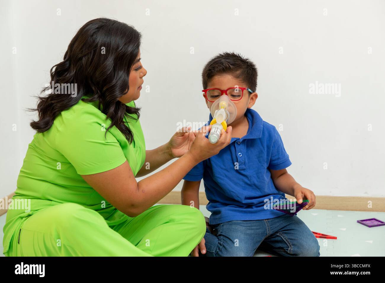 Pediatric nurse helping child using inhaler for respiratory therapy ...