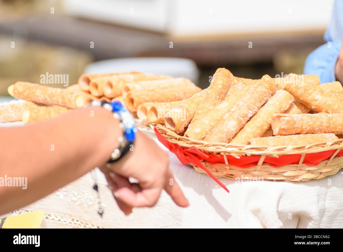 hand of a woman buying traditional fried puff pastry at a street food ...