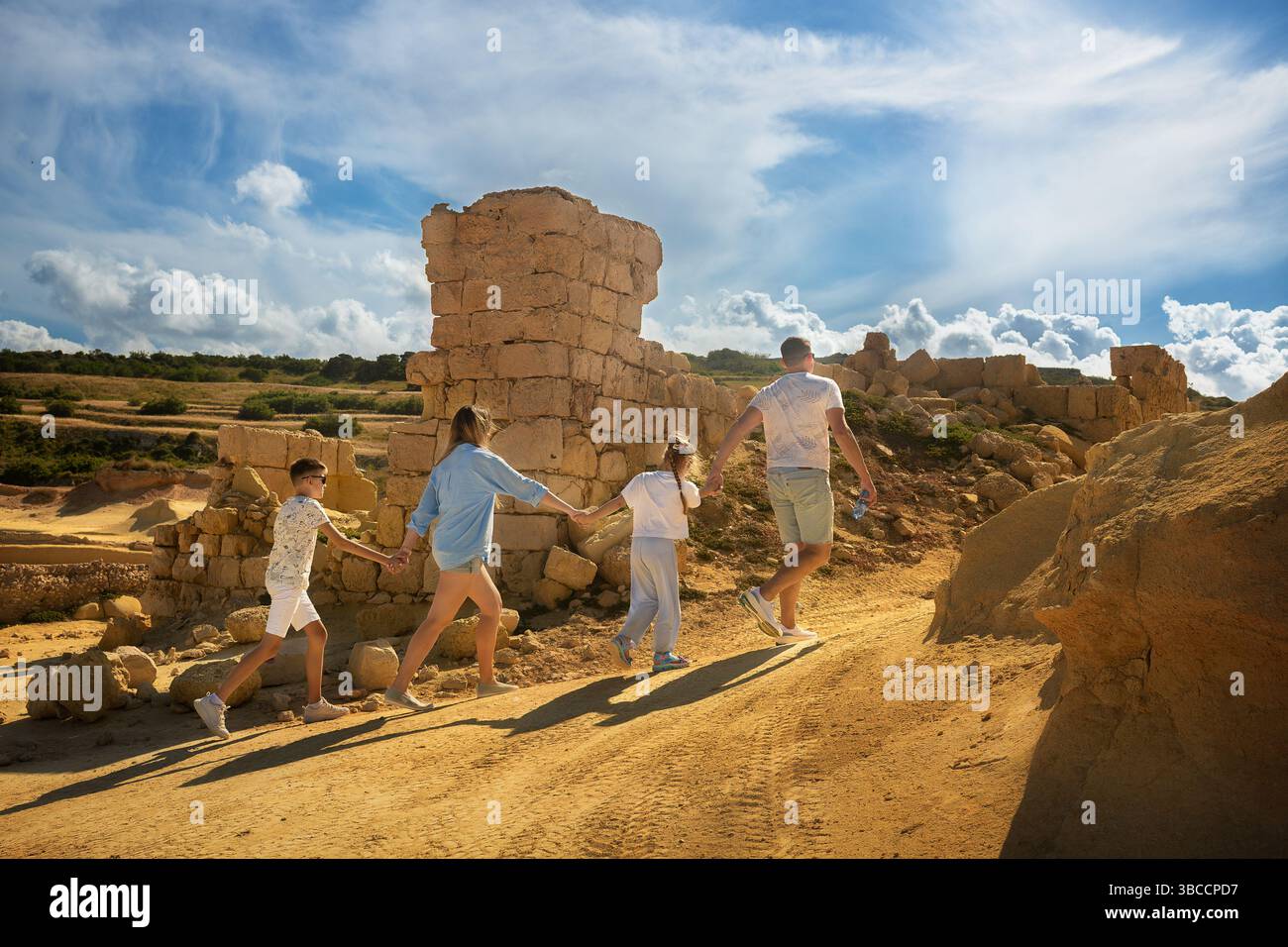 A happy family with two children walks hand in hand in a line across a ...