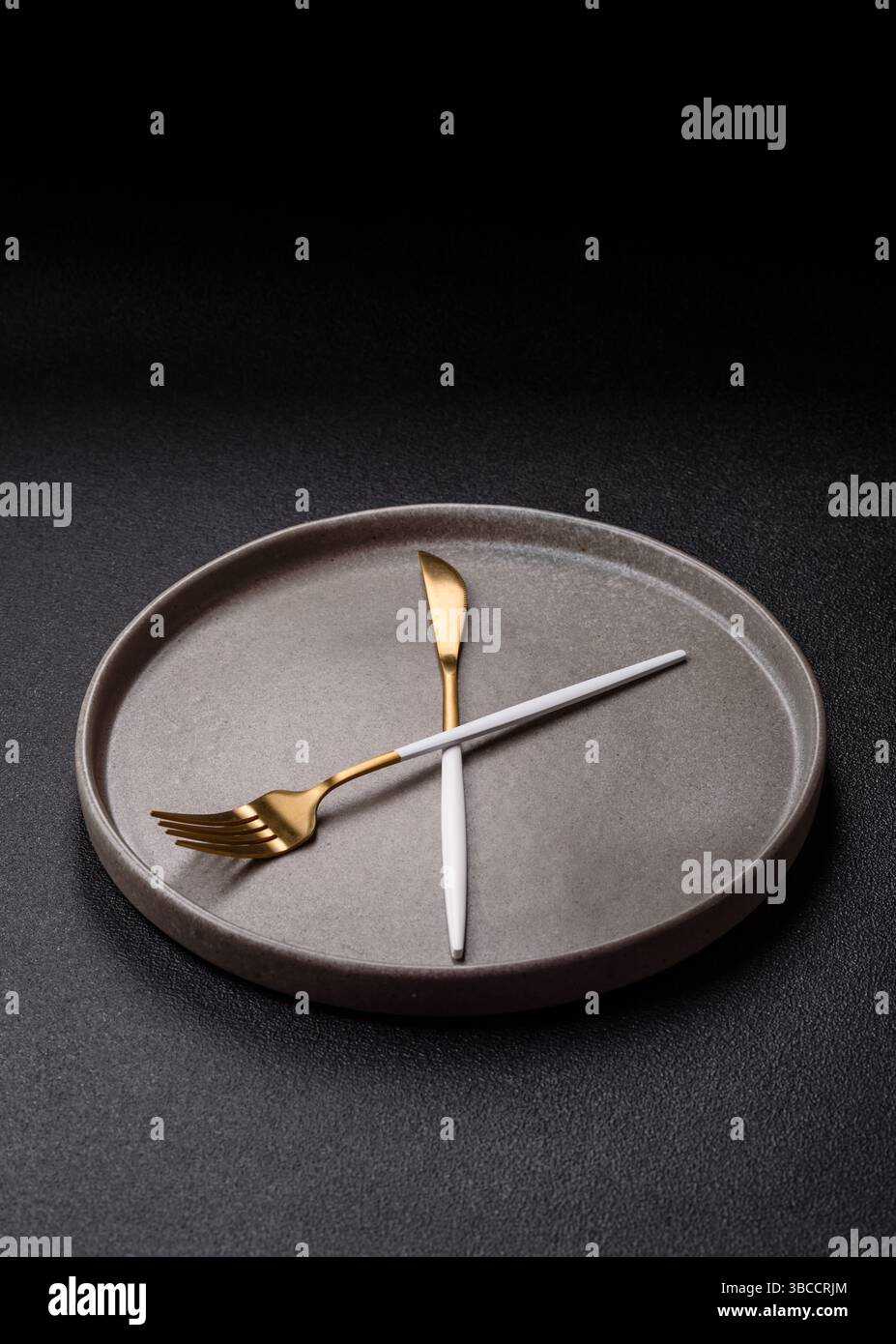 Empty plate with devices in the form of clock hands as a conceptual ...