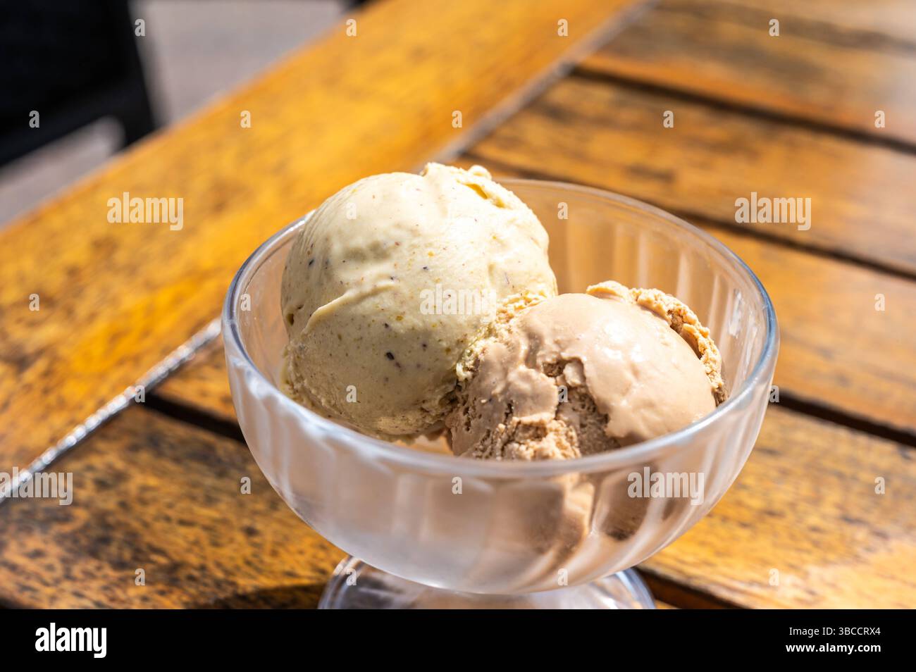 Two scoops of icecream in a glass bowl on a wooden table in Kruibeke ...
