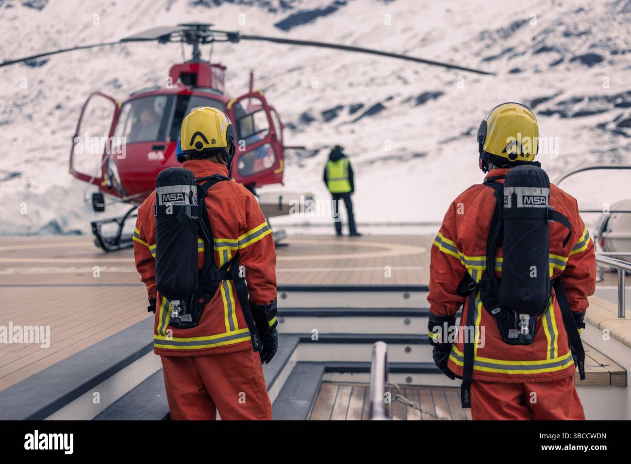 Fire crew in full gear stand by a helicopter on a superyacht helideck ...