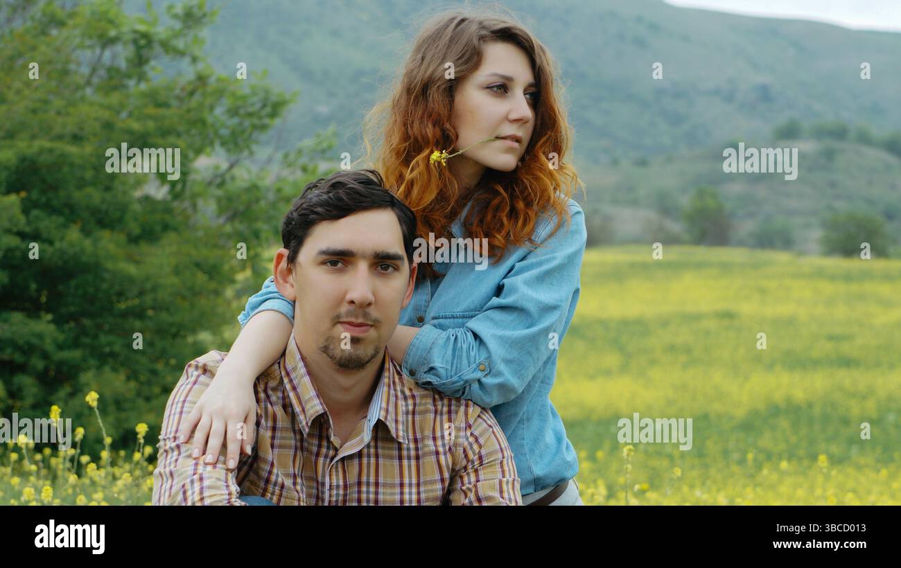 Young romantic couple standing in a blooming spring field. The woman ...