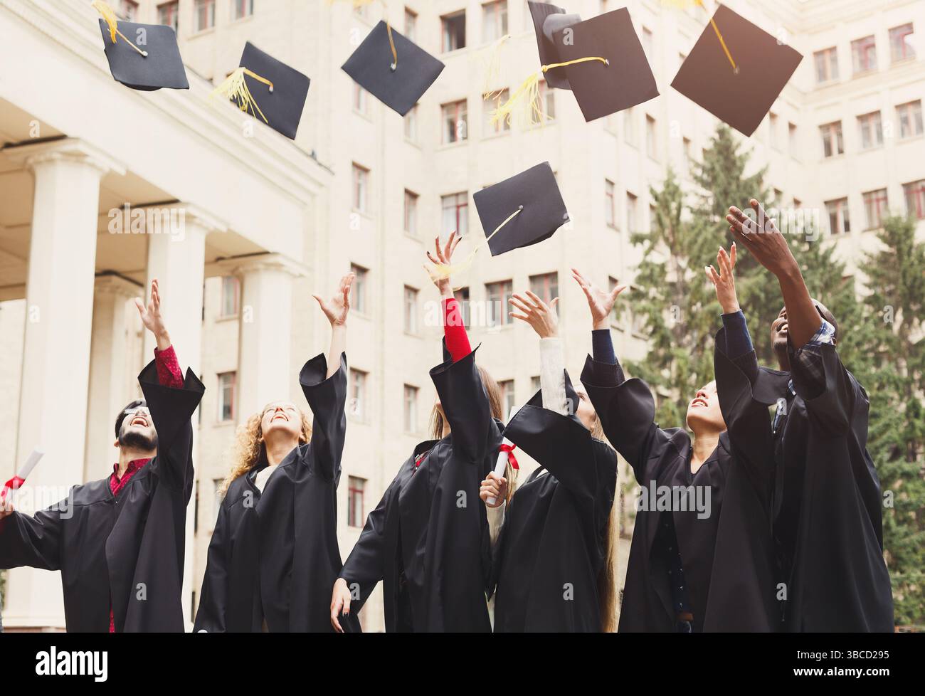 A group of graduates throwing graduation caps in the air Stock Photo ...