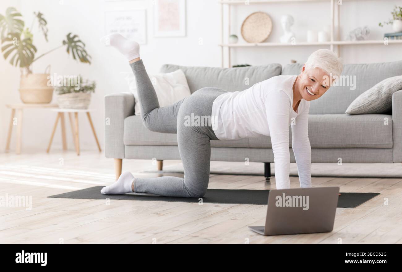 Fitness at home. Sporty senior woman exercising in front of laptop ...