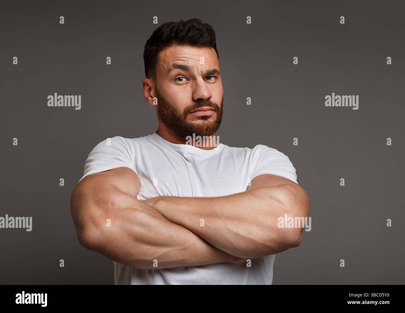 Suspicious young man with crossed big muscular arms Stock Photo - Alamy