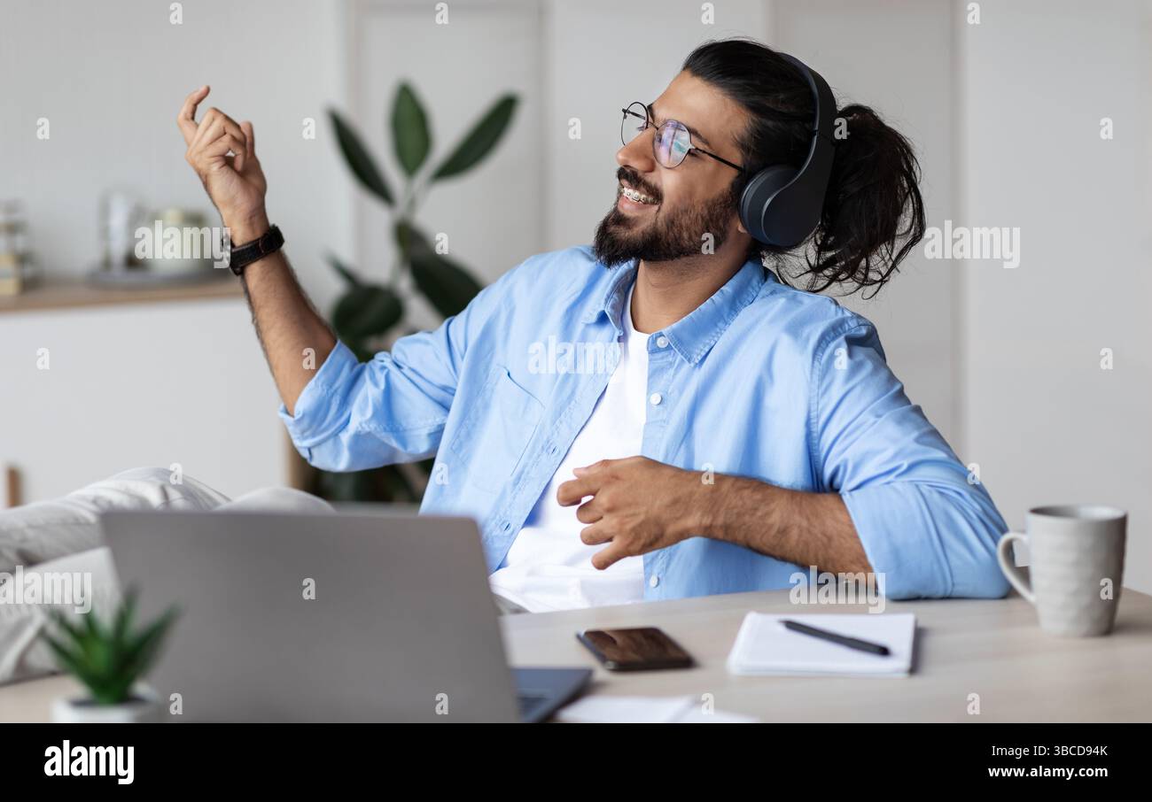 Break at work. Joyful african american businessman listening music in ...