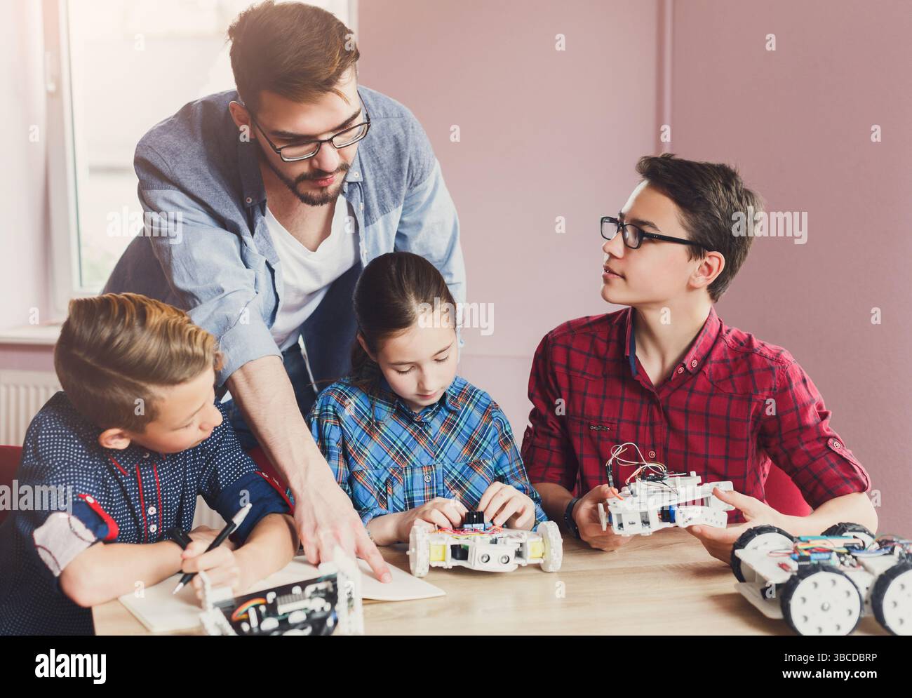 Stem education. Kids creating robots with teacher Stock Photo - Alamy