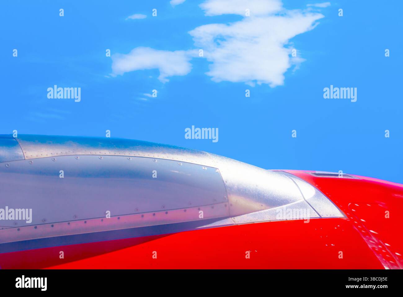 Shiny aircraft surface likely fuselage in flight, with a vibrant red ...