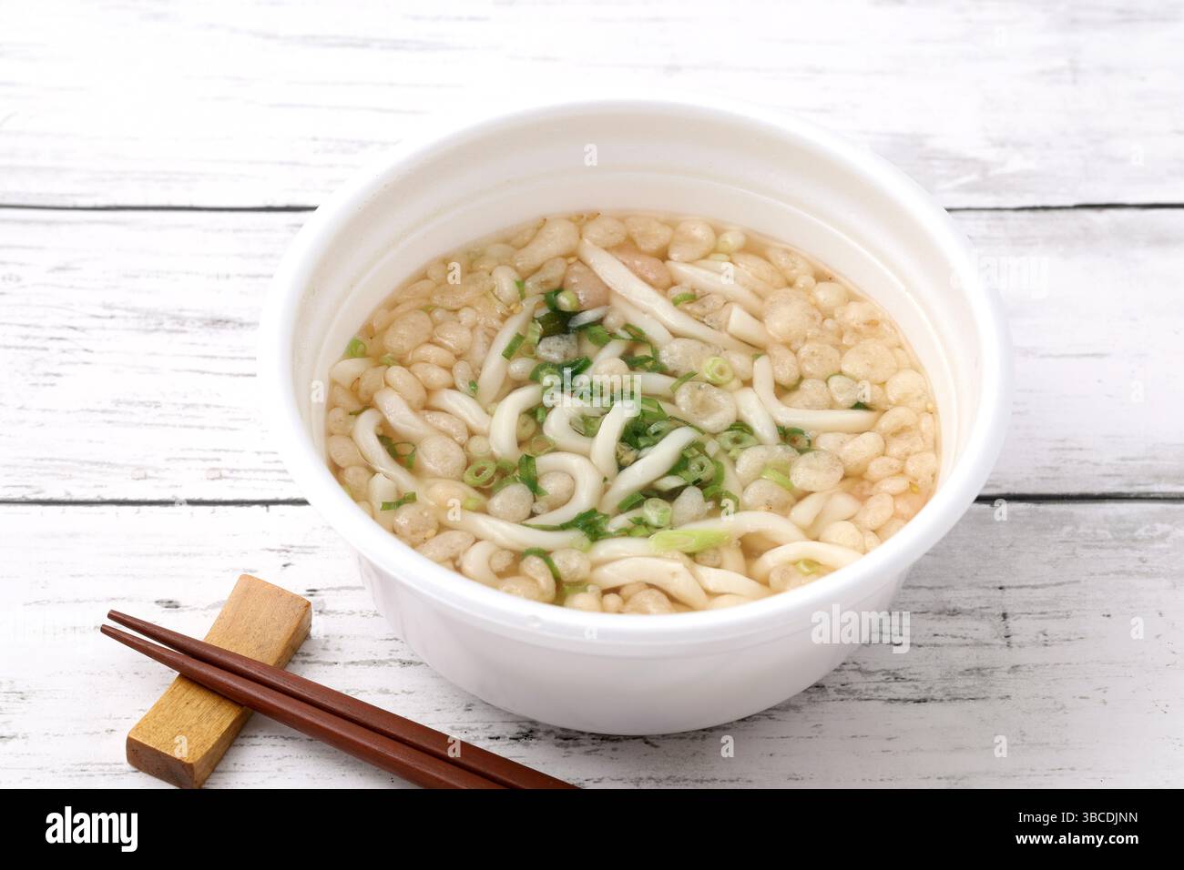 Boiled instant Tanuki Udon noodles in a plastic cup with chopsticks on ...