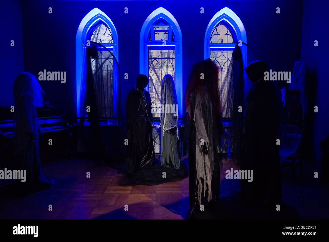 Darkly lit Halloween-themed room featuring life-size grim reaper ...