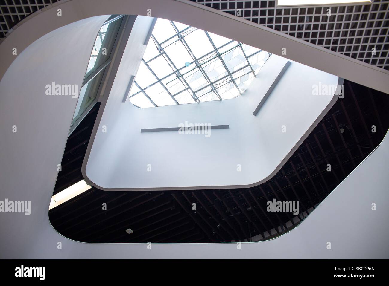 Looking upward at a bright skylight in a contemporary atrium featuring smooth white walls and ...