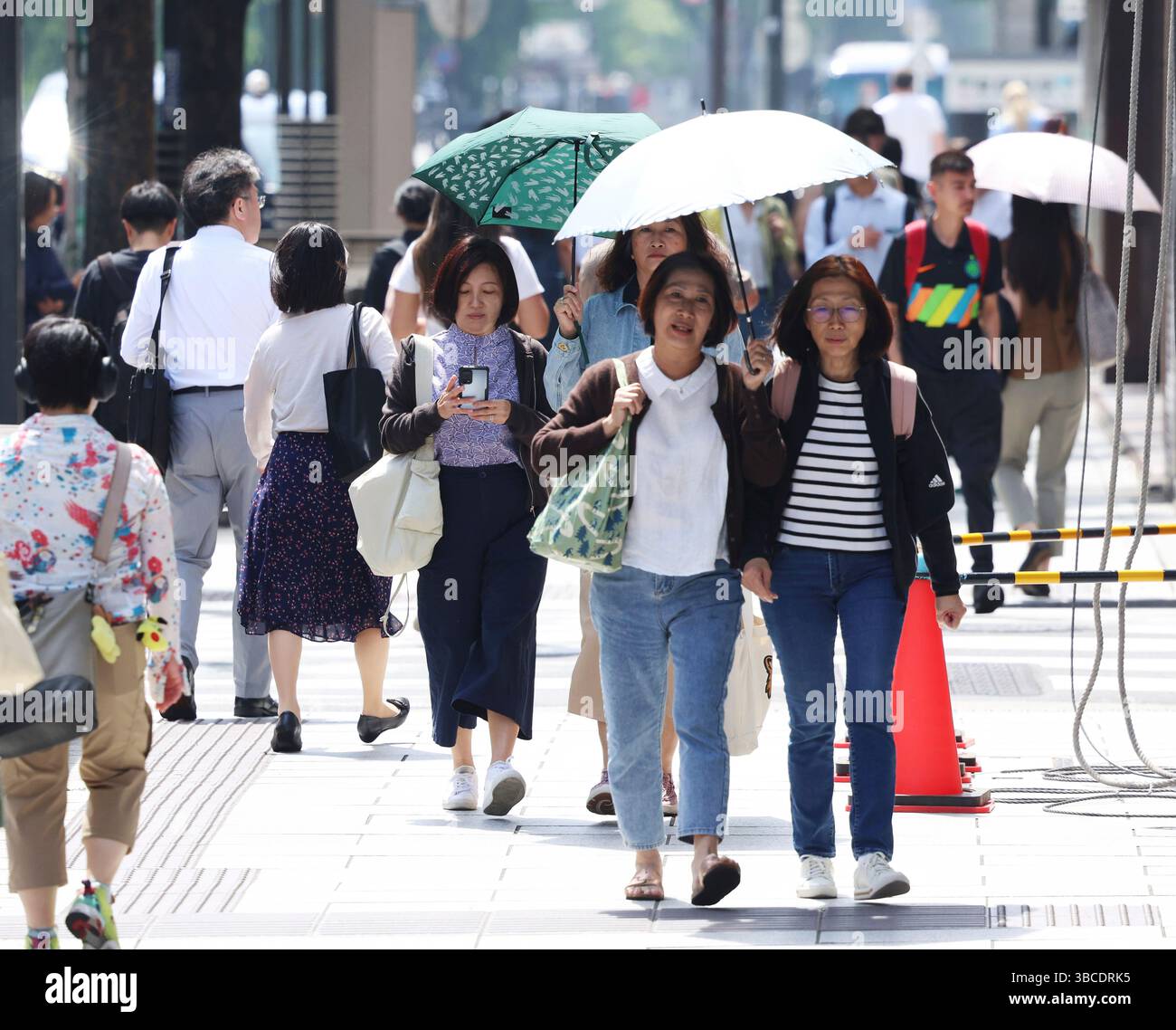 People walk on a street while the temperature rising at Ginza district in Chuo Ward, Tokyo on ...