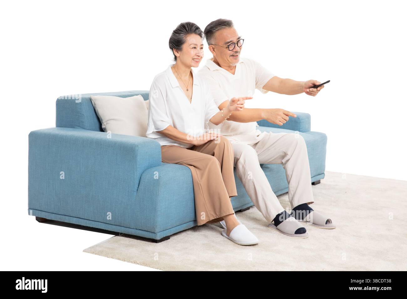 An elderly couple sitting on the sofa watching TV with a remote control ...