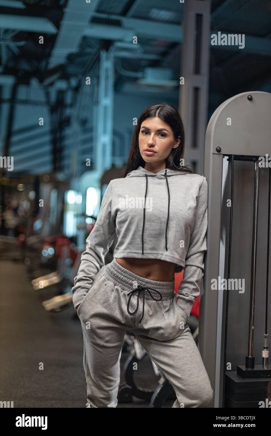 determined young woman dressed in athletic wear stands confidently near ...
