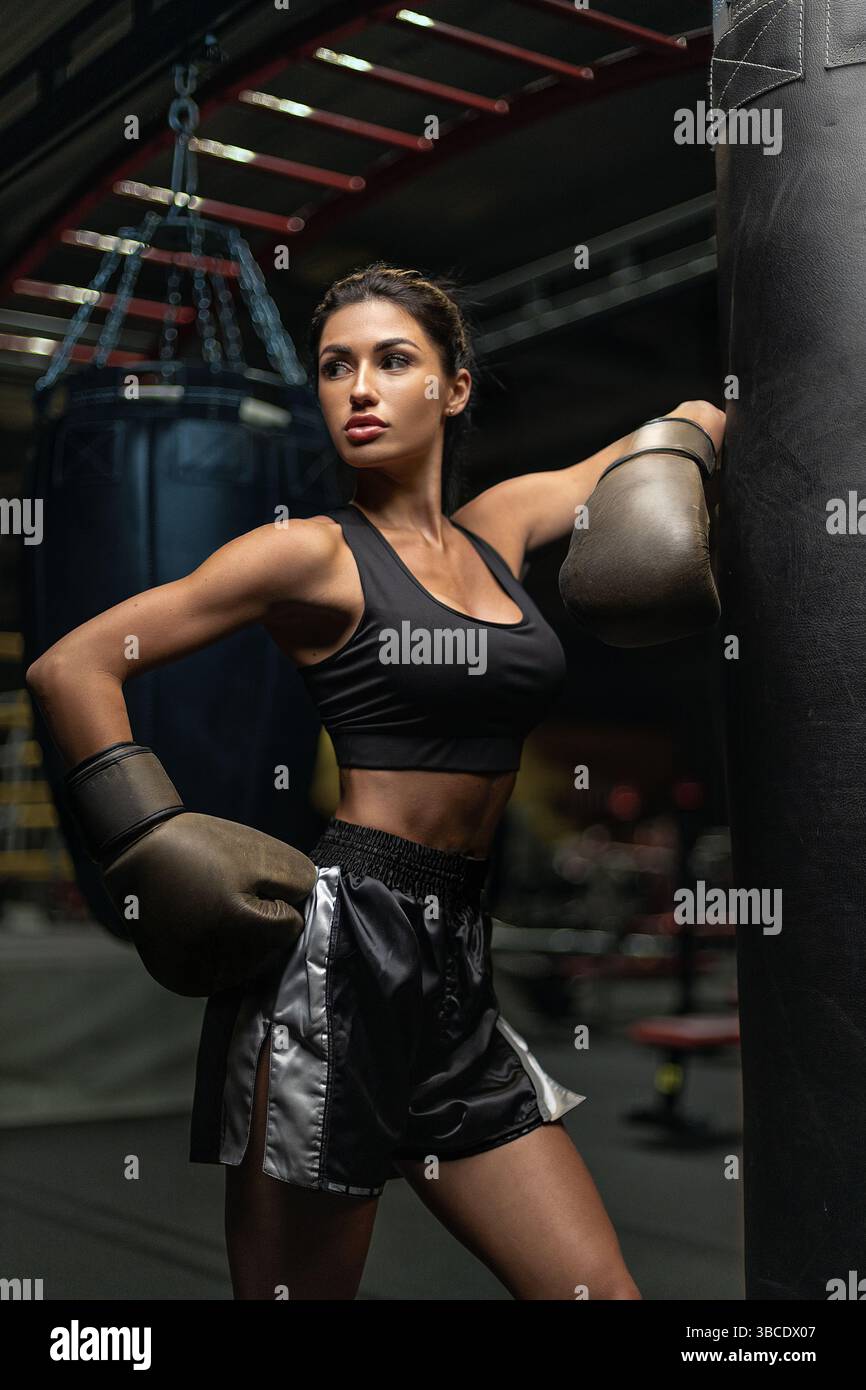female boxer wearing boxing gloves and shorts prepares to strike a ...