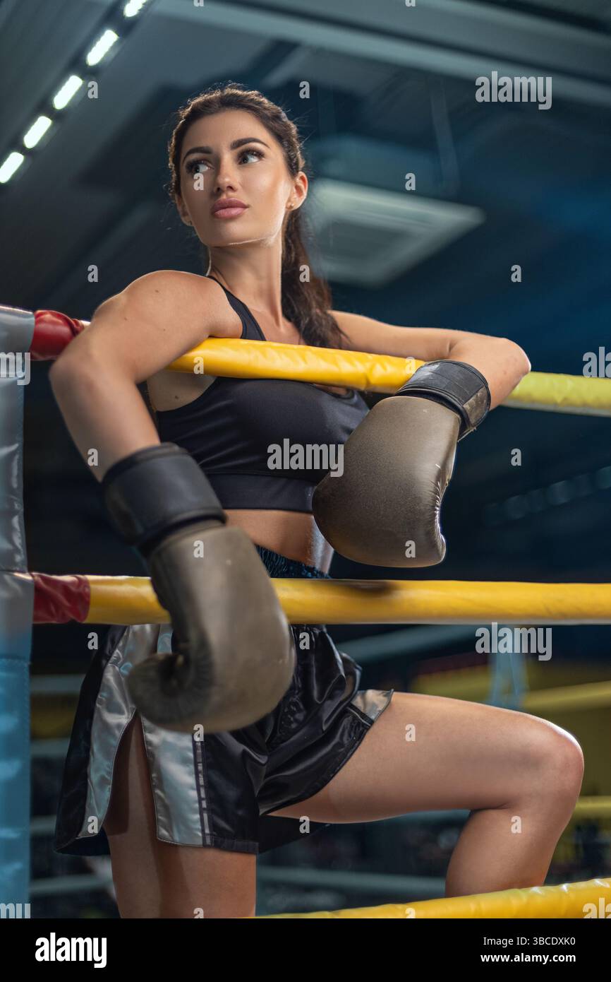 dedicated boxer leans against the ropes of a boxing ring in a gym ...