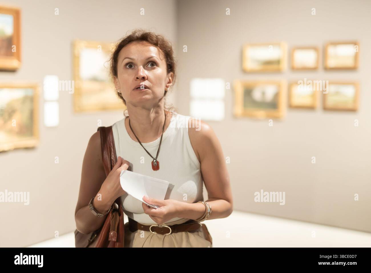 Woman viewing art gallery with brochure Stock Photo - Alamy