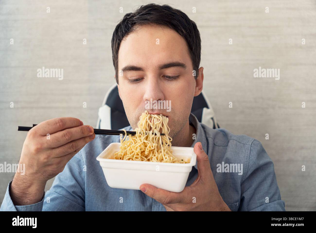 Young man eating instant noodles while working with in office. Lunch at ...