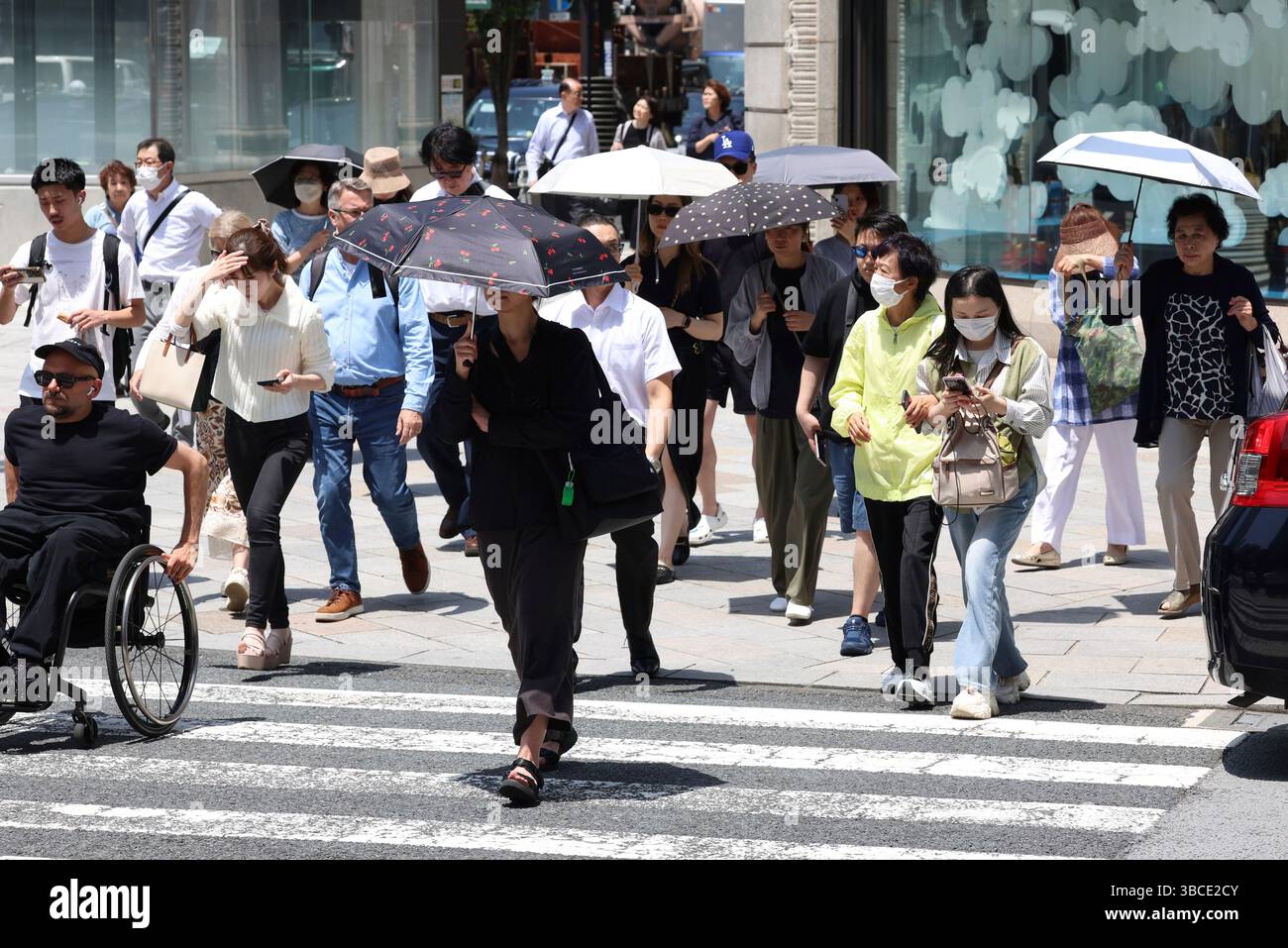 People walk on a street while the temperature rising at Ginza district in Chuo Ward, Tokyo on ...