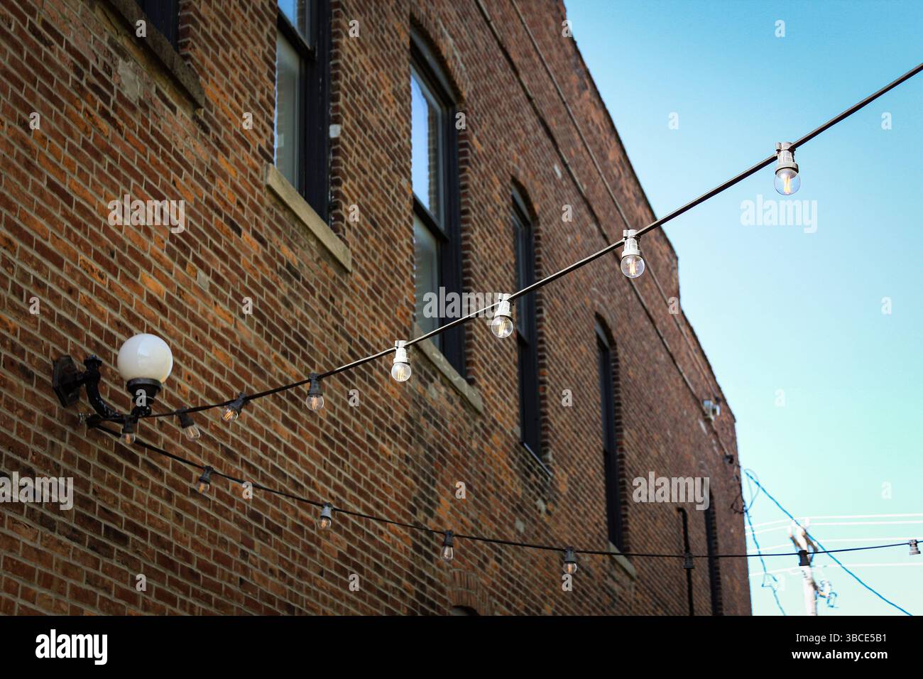 brick facade with windows and string lights isolated against a blue sky ...