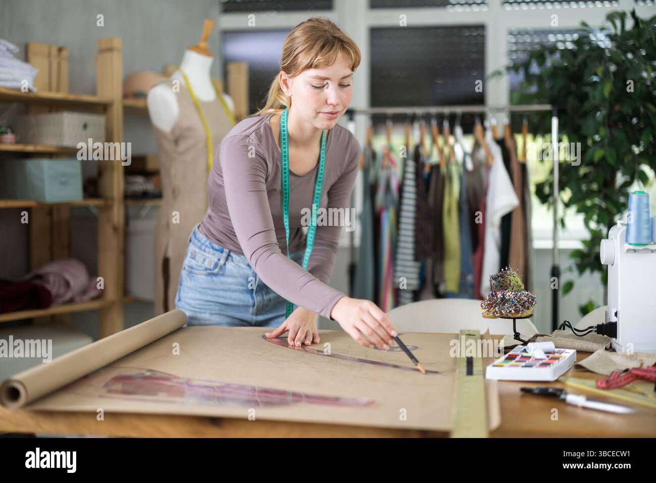 Female seamstress drawing sewing pattern on paper in studio Stock Photo ...