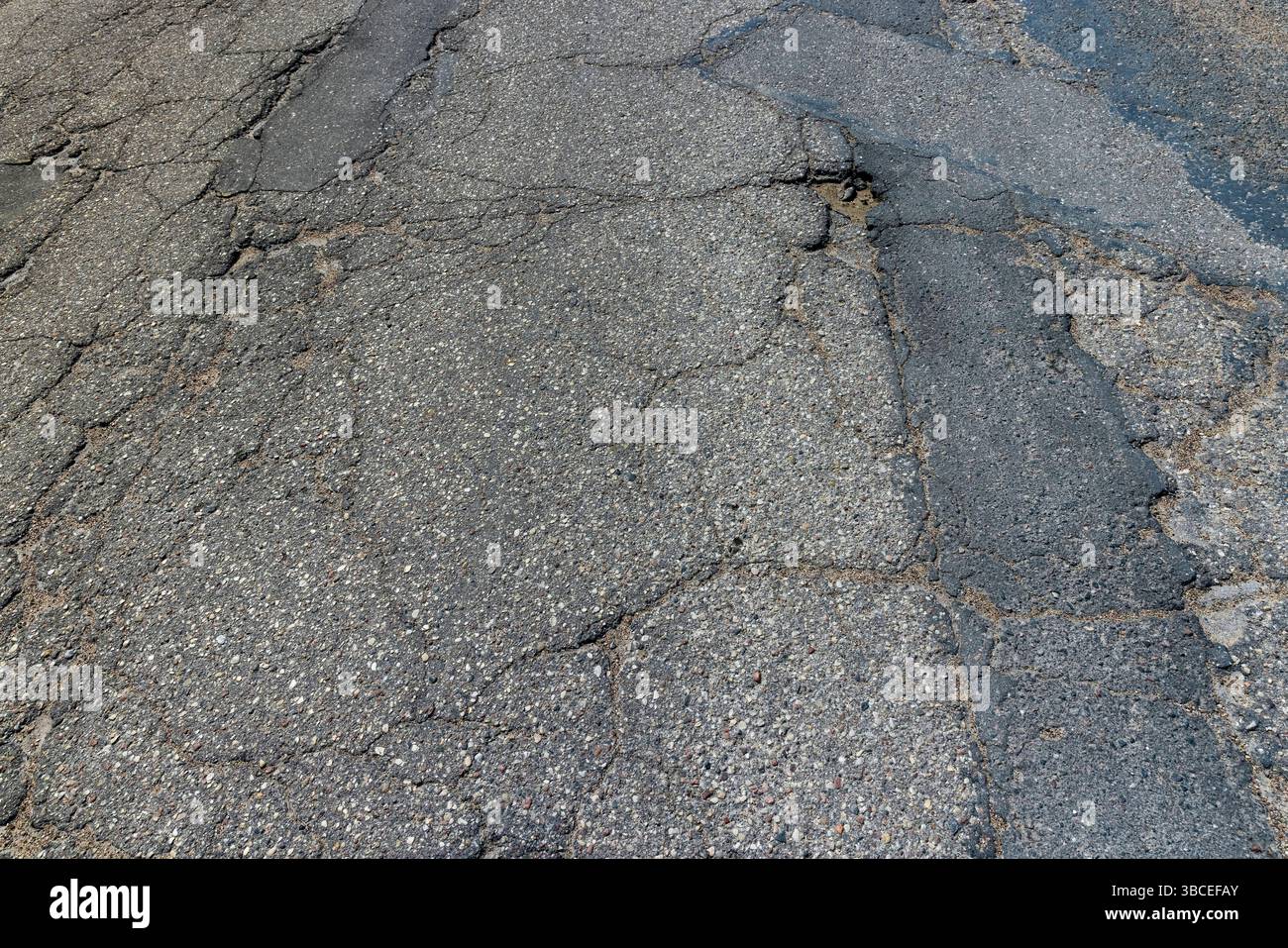 An old paved road with a lot of holes and damage, very poor quality of ...