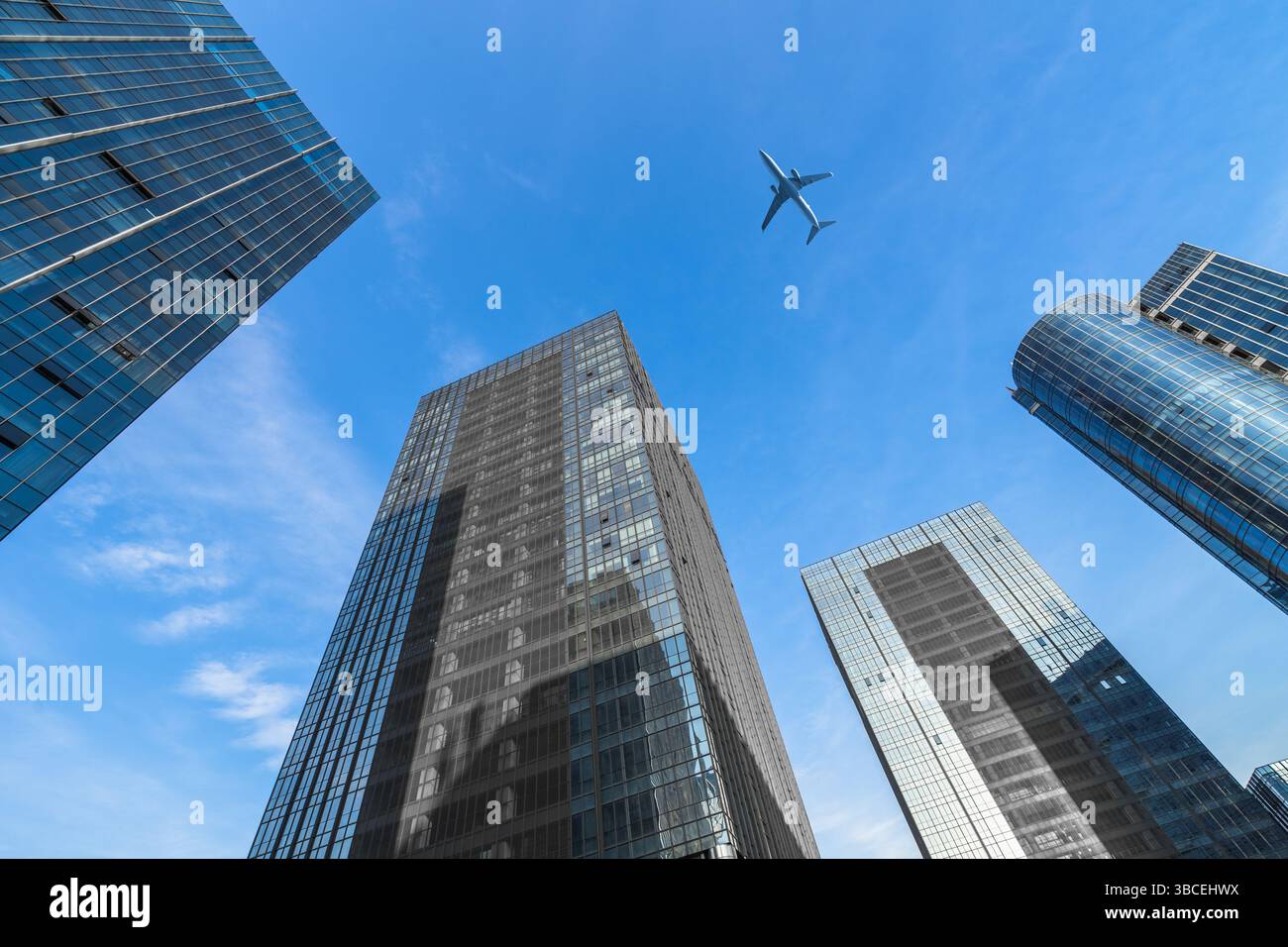 Tall city buildings and a plane flying overhead Stock Photo - Alamy