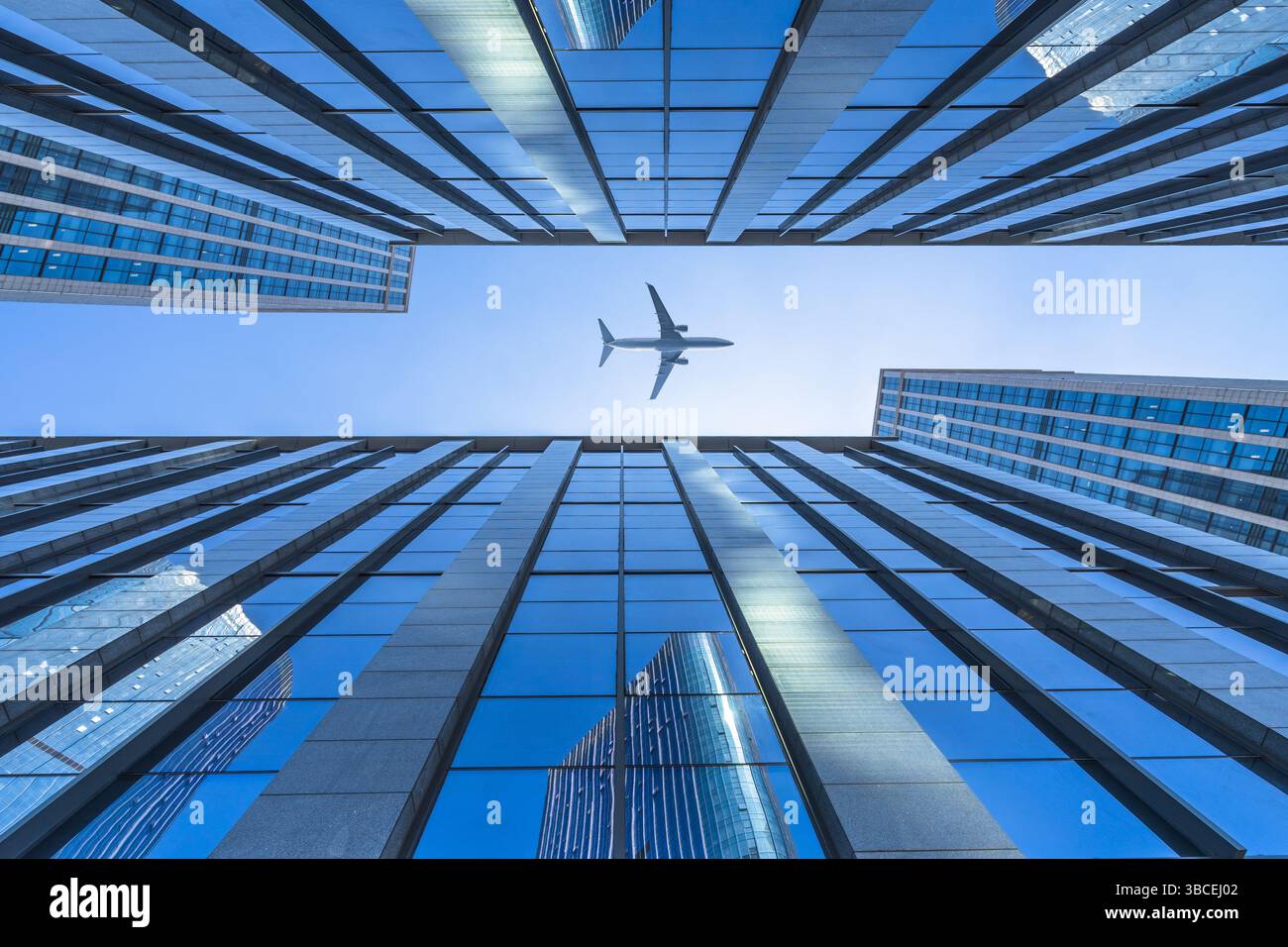 Tall city buildings and a plane flying overhead Stock Photo - Alamy