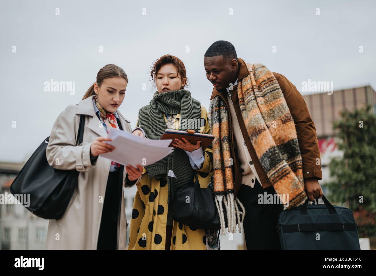 Collaborative group of people reviewing project details outdoors in ...