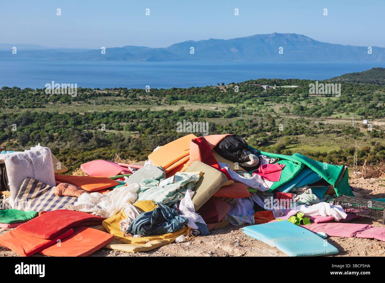 A pile of discarded cushions, textiles, and household waste lies ...