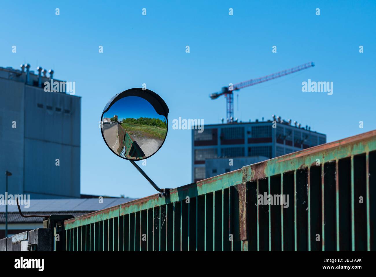 A circular mirror reflects a construction site with workers on a ...