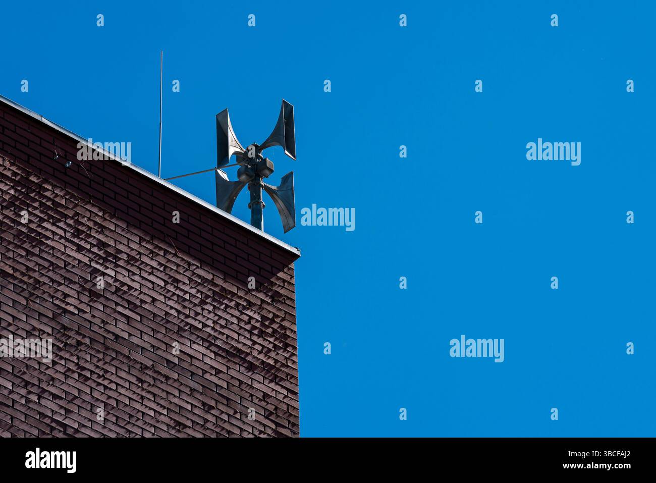 A siren is mounted on the edge of a rooftop, contrasting with a vibrant ...