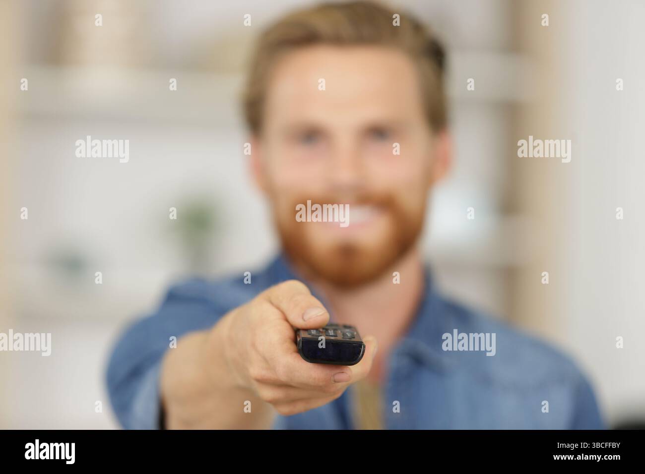 man on the couch switches remote control tv channels Stock Photo - Alamy