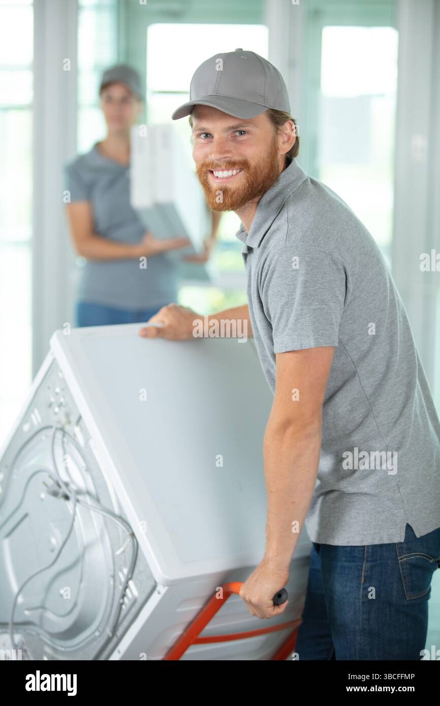repairman carrying washing machine with hand truck Stock Photo - Alamy