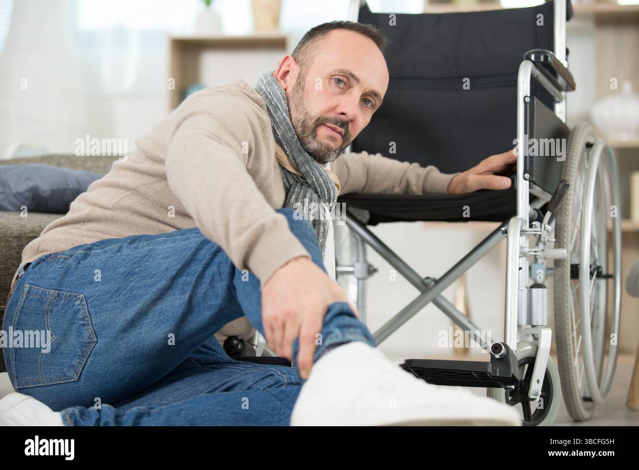 paralysed man sat on the floor beside his wheelchair Stock Photo - Alamy
