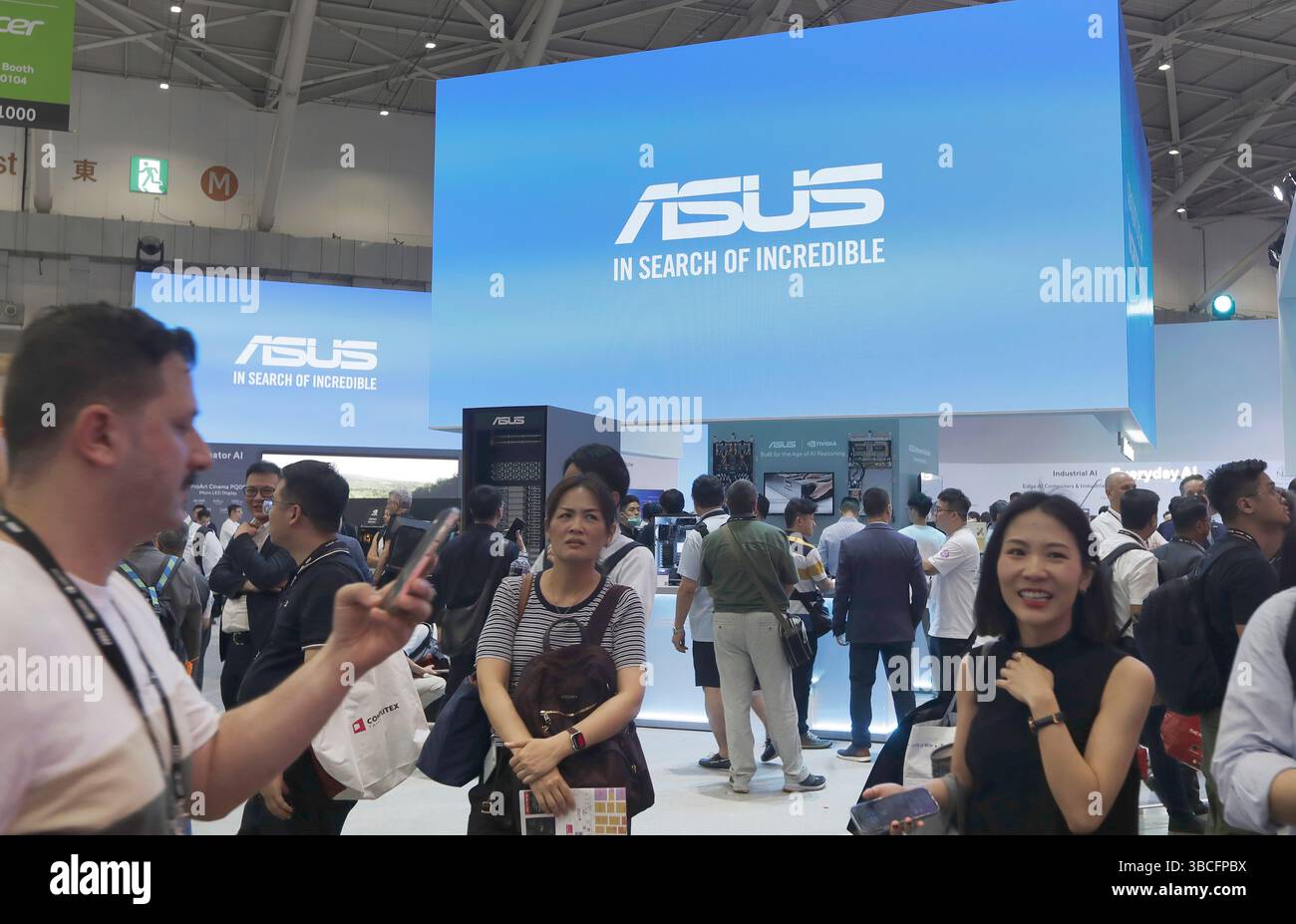 Visitors walk by Asus booth at the Computex Taipei exhibition, one of ...