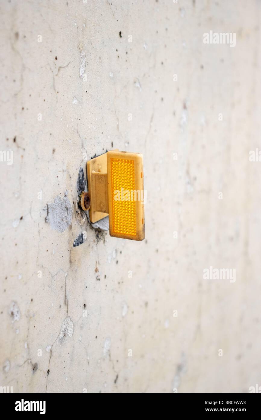 orange warning reflector attached to a white wall with fading and ...