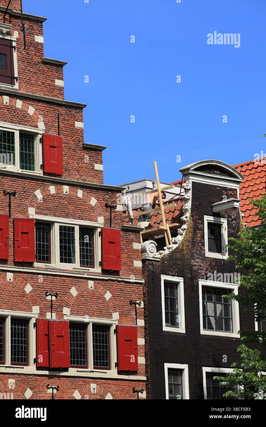 Typical old Dutch house facades with different gables close up with man ...