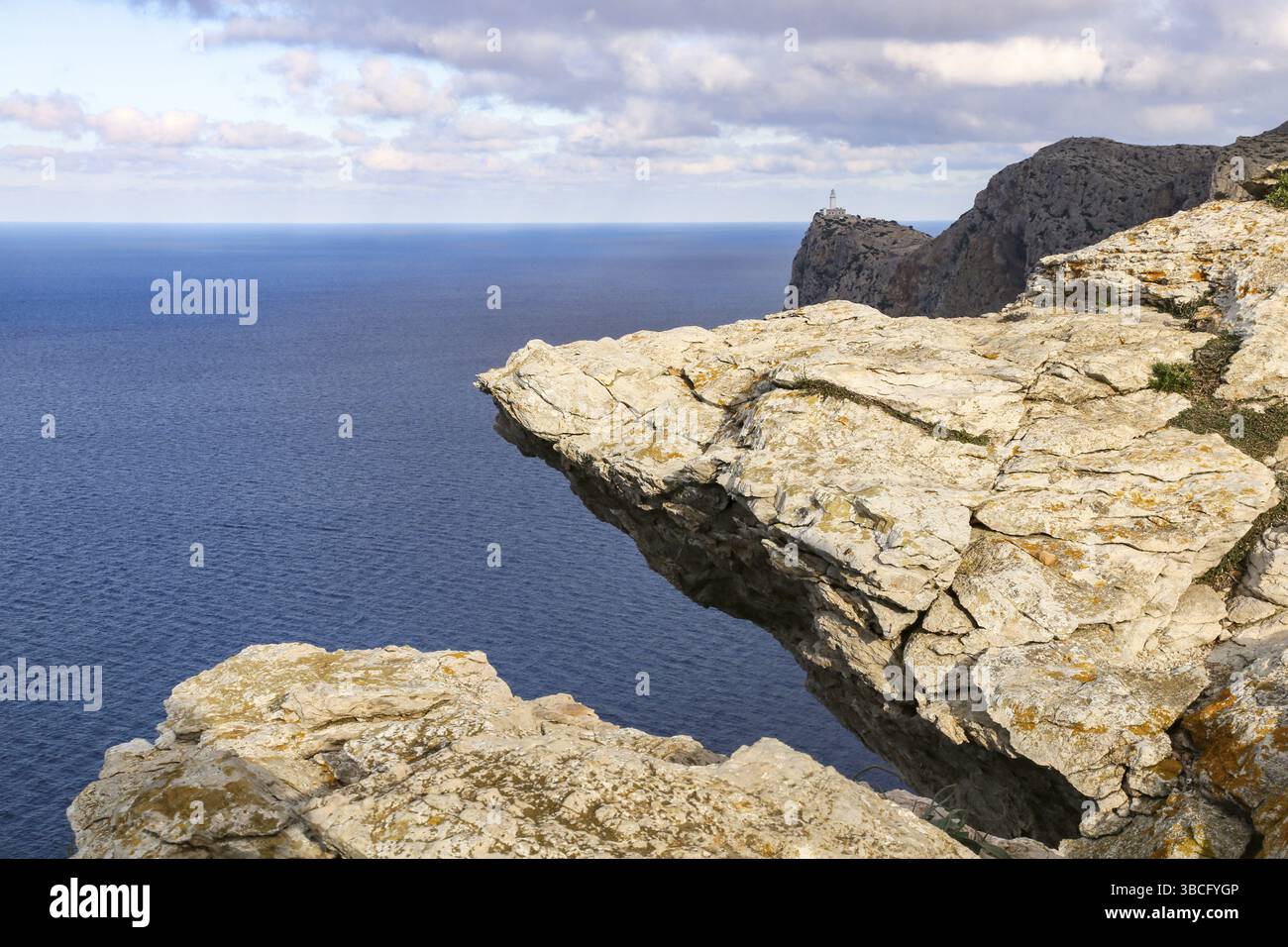 Rock in front of lighthouse towers over blue sea Stock Photo - Alamy