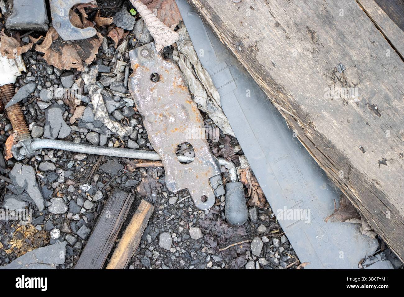 pile of dirt and old tarmac with litter and car parts on the road side ...