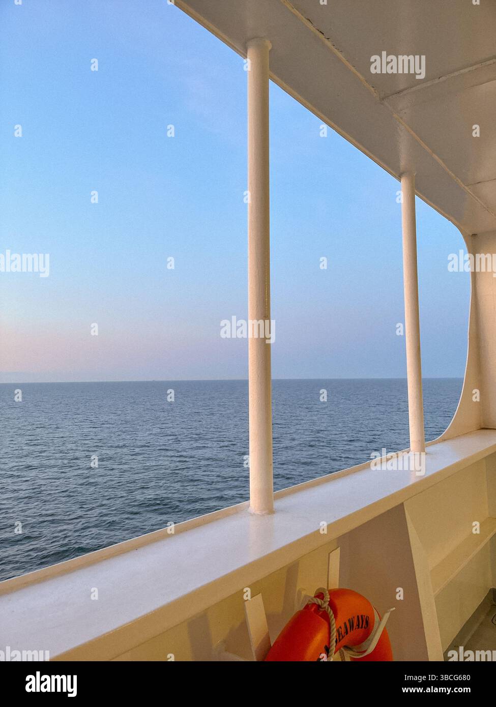 View of calm ocean horizon at sunset from the deck of a ship, with ...